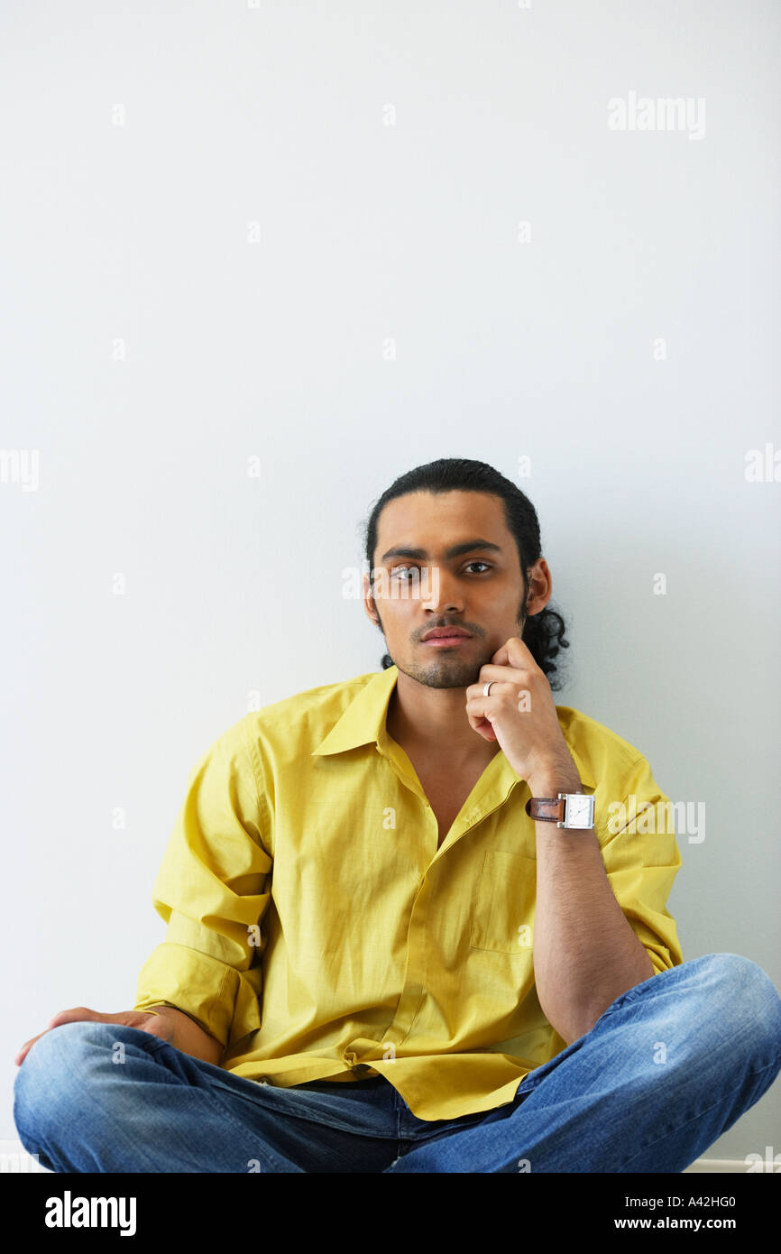 Portrait of man sitting on floor with hand on face Stock Photo - Alamy