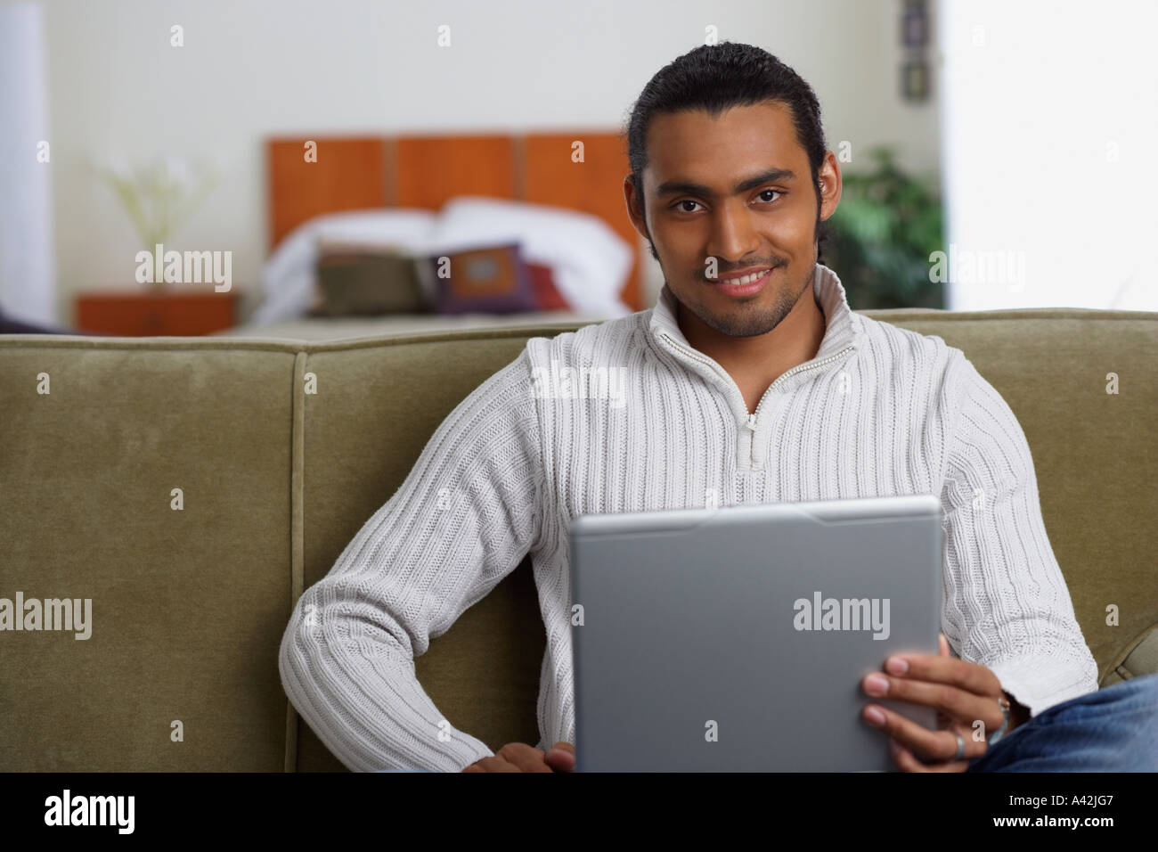 Portrait of man sitting on couch with computer Stock Photo - Alamy