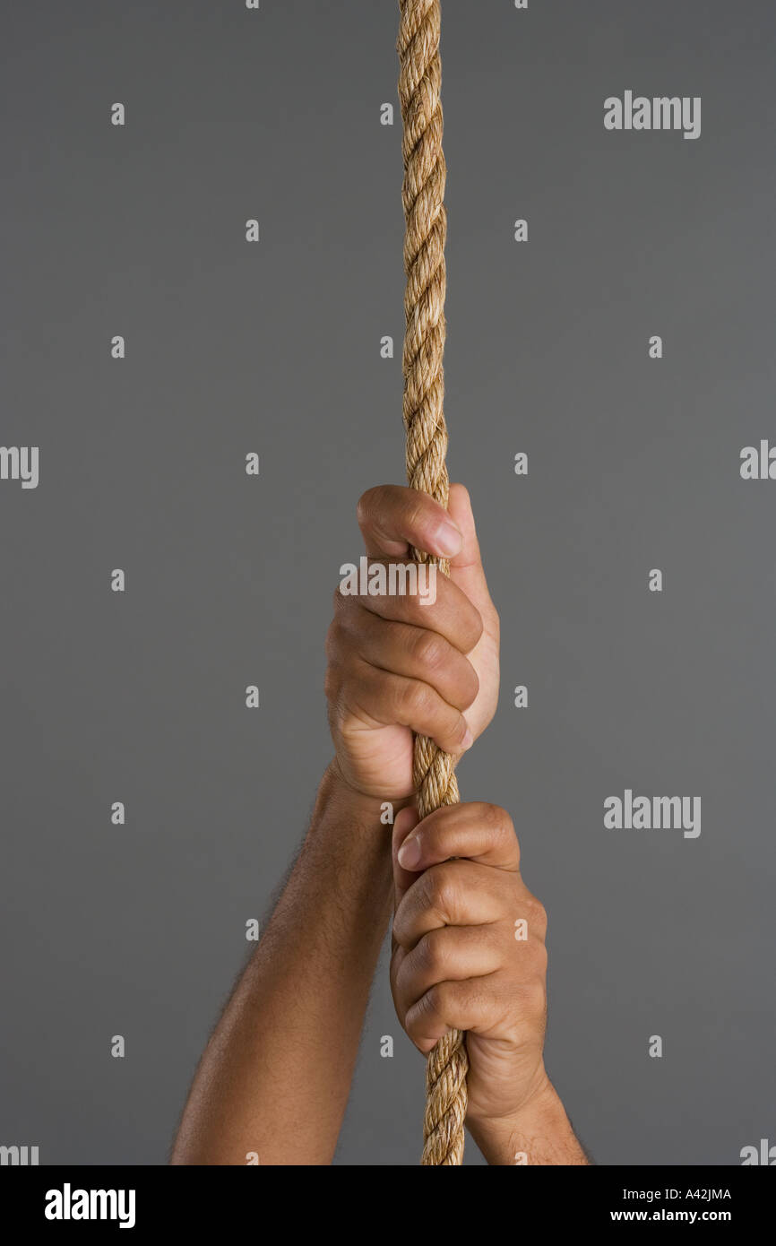 Close up of two hands hanging on rope Stock Photo - Alamy