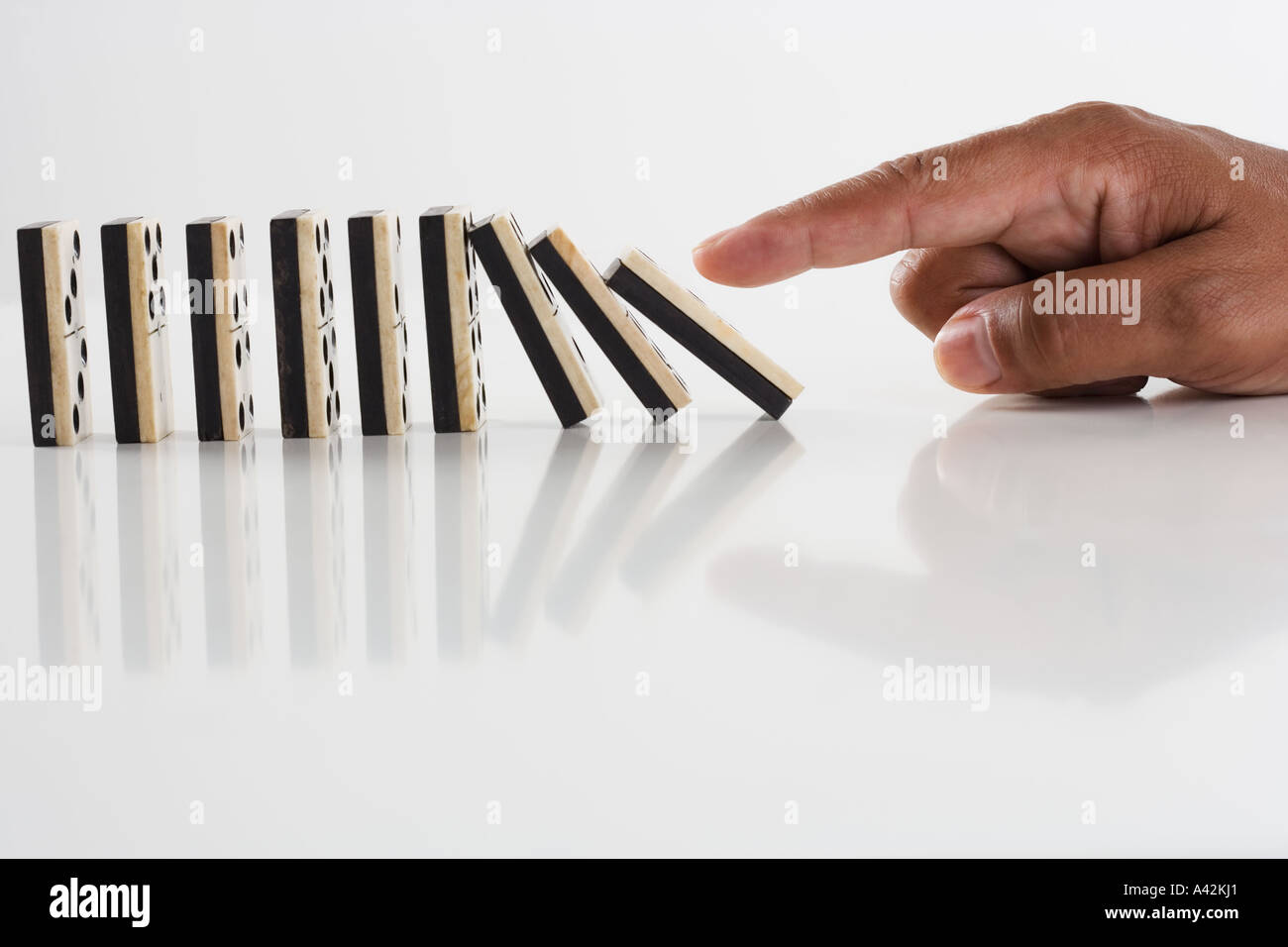 Close up of hand knocking dominos over Stock Photo - Alamy
