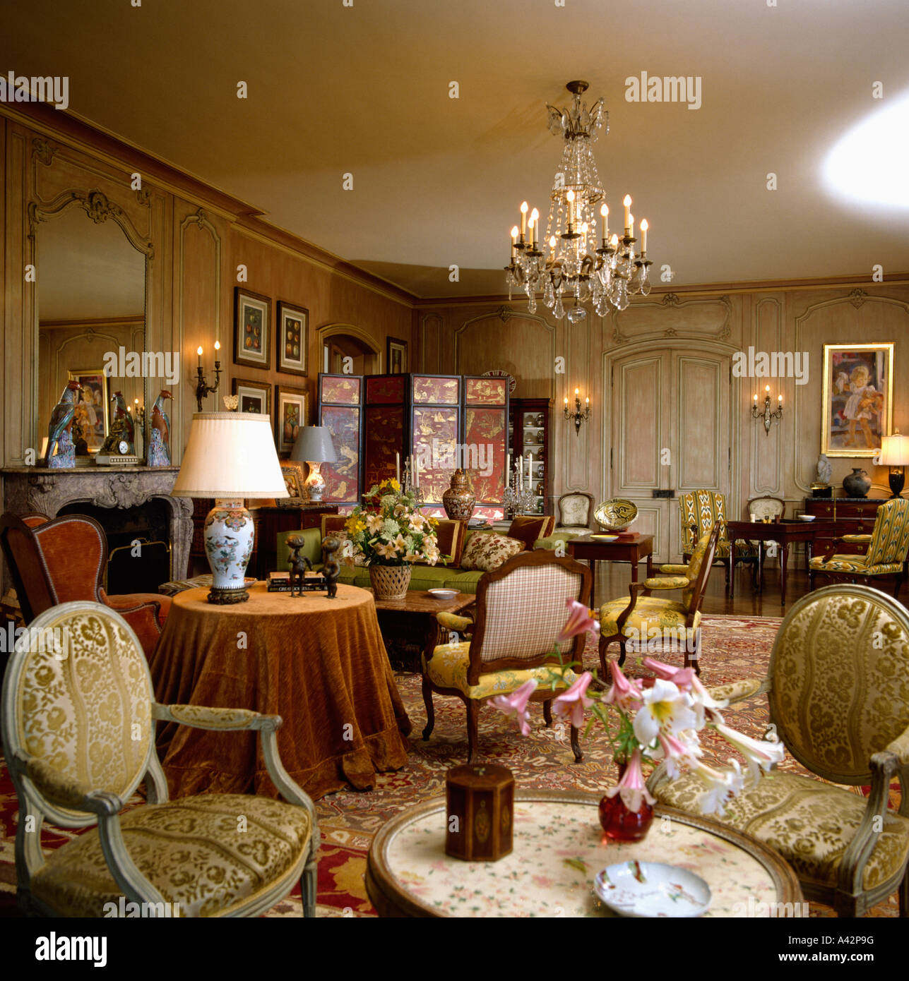 Chandelier in traditional sittingroom with lighted lamp on table with ...