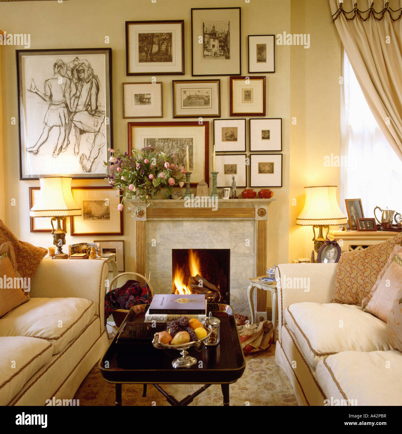 Cream settees on either side of fireplace with pictures above in ...