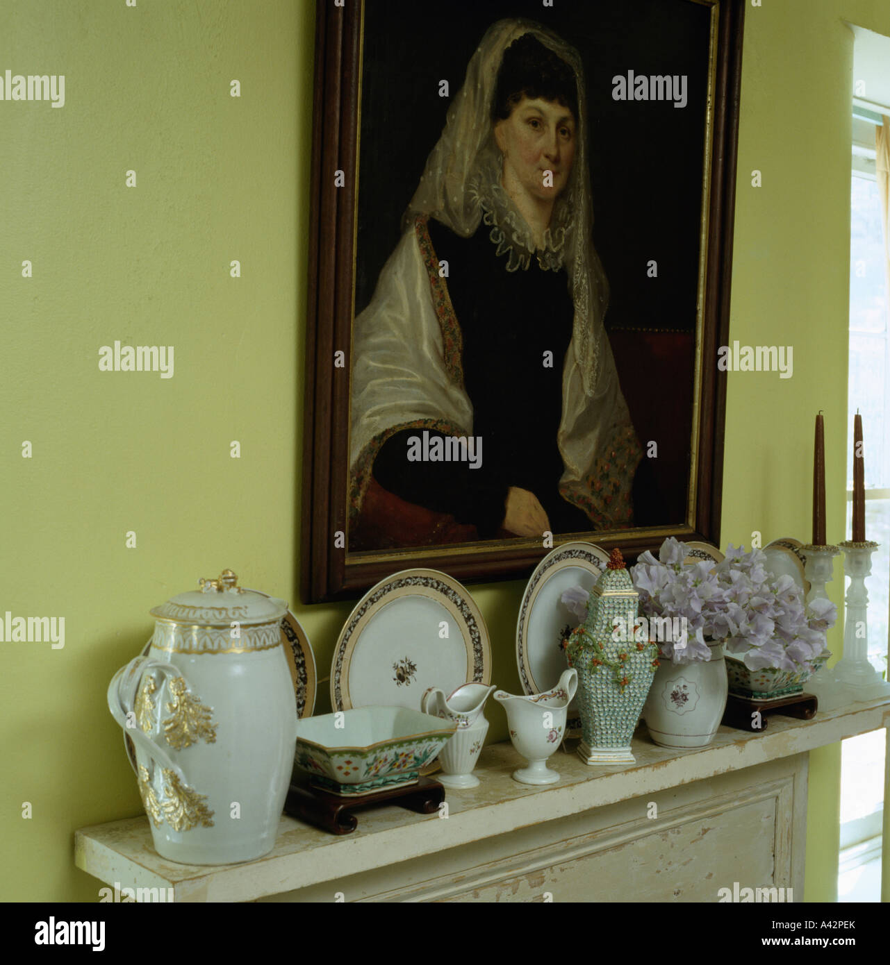 Close-up of large portrait above mantelpiece with collection of antique ...