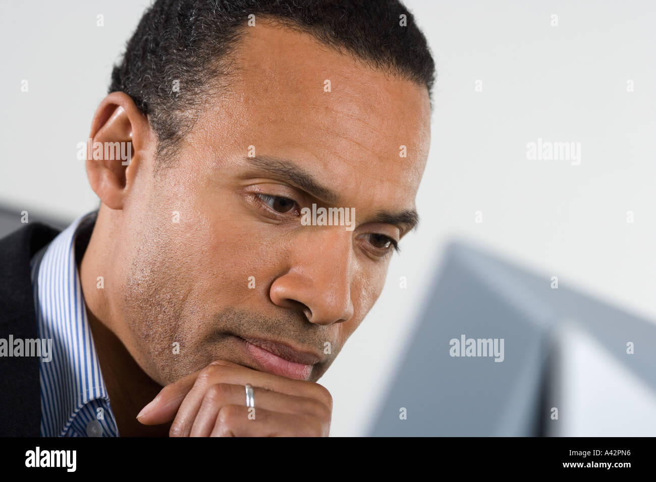 Man thinking with hand on chin while looking at computer Stock Photo ...
