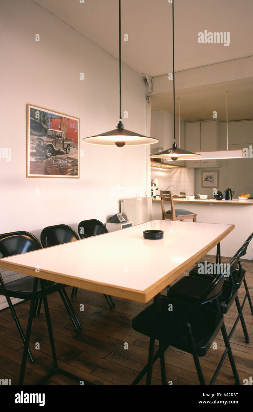 Modern suspended lights above wooden table with black chairs in modern ...