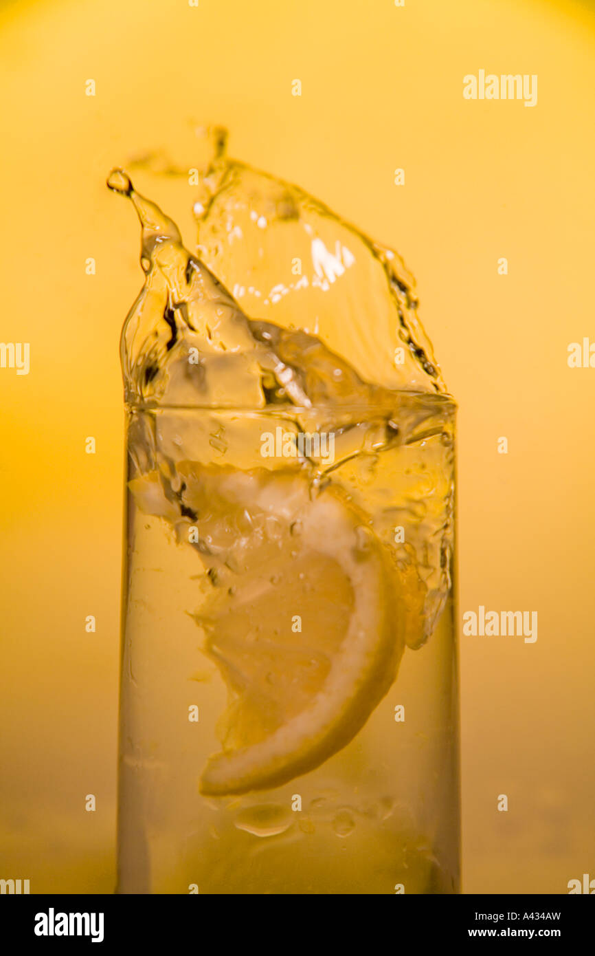 Slice of lemon splashing into glass of water Stock Photo - Alamy