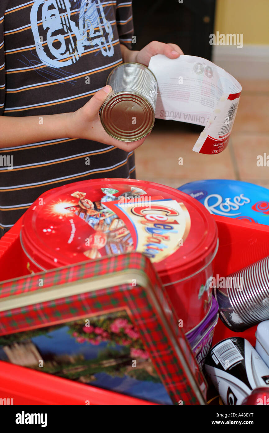 A young child peels off paper labels on metal steel tin cans preparing ...