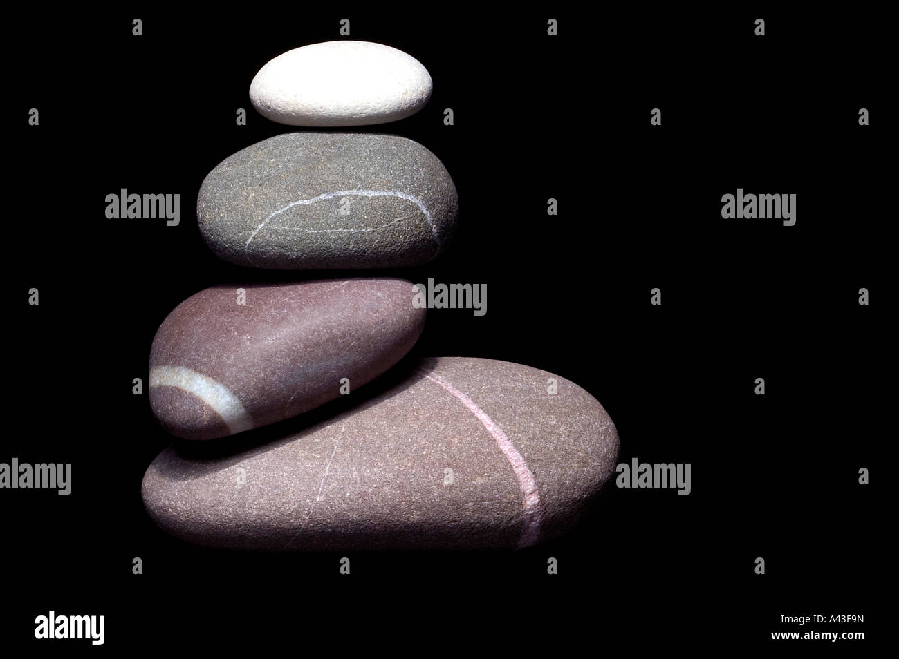 Pebble sculpture with harsh lighting from above on a black background ...