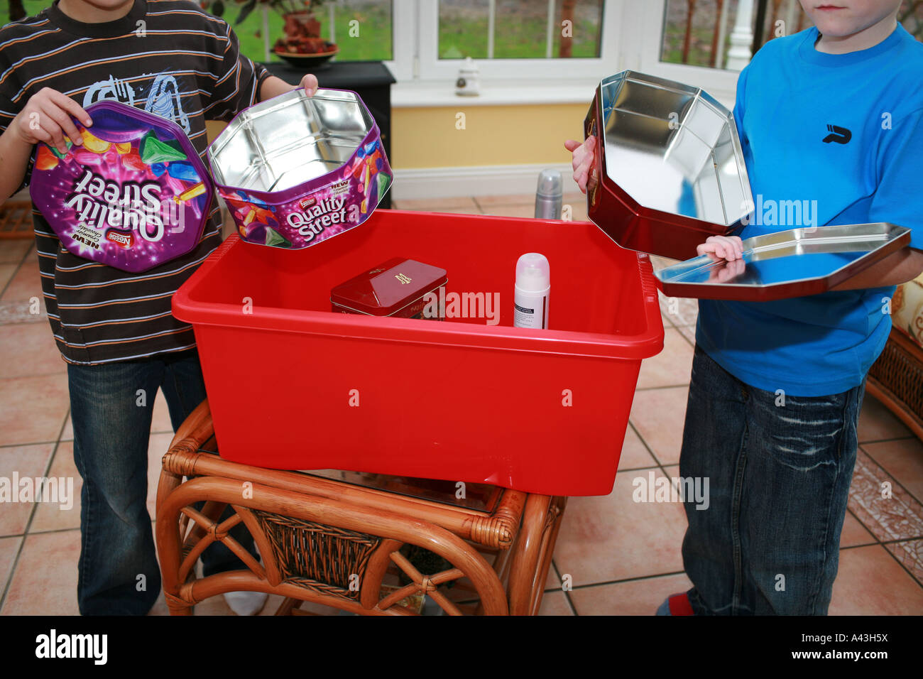 Young children arrange recyclable metal steel tin can household waste ...