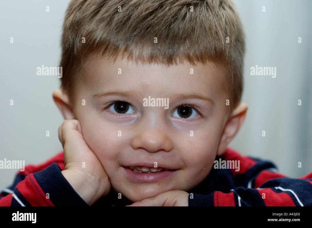 Closeup of young boy smiling with hand on face Stock Photo - Alamy