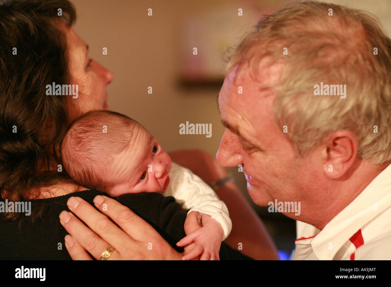 Proud first time Grandparents hold a cute 3 three day old newborn baby ...