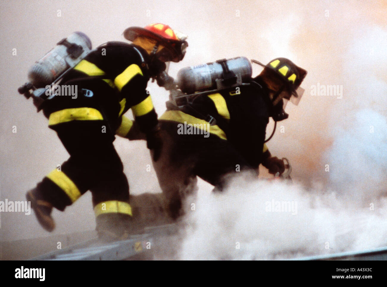 Two fire fighters on roof cutting ventilation hole while smoke ...