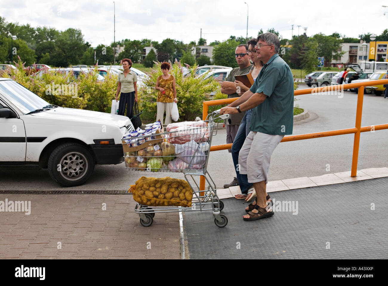 SLOVAKIA Sturovo Man push grocery shopping cart down ramp to parking ...
