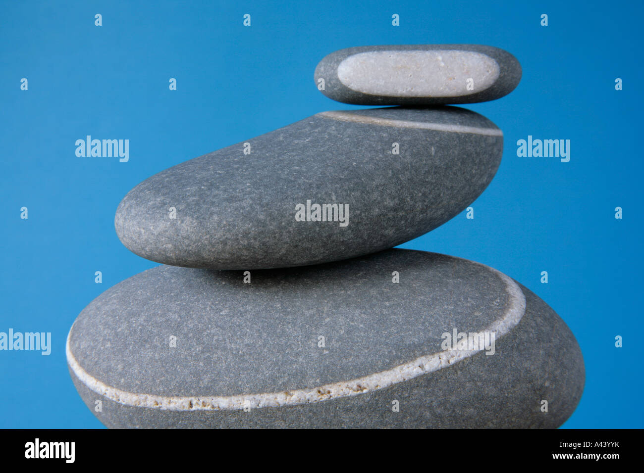 Three smooth old grey stones with embedded white circles in balance ...