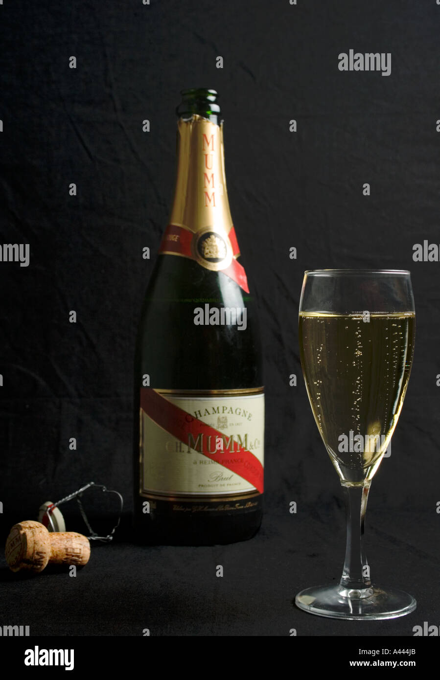 An open bottle of Mumm Champagne with wire cage cork and a glass of ...