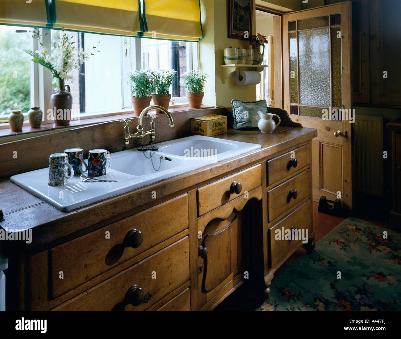 Double white sinks in pine wood kitchen unit below window with yellow ...