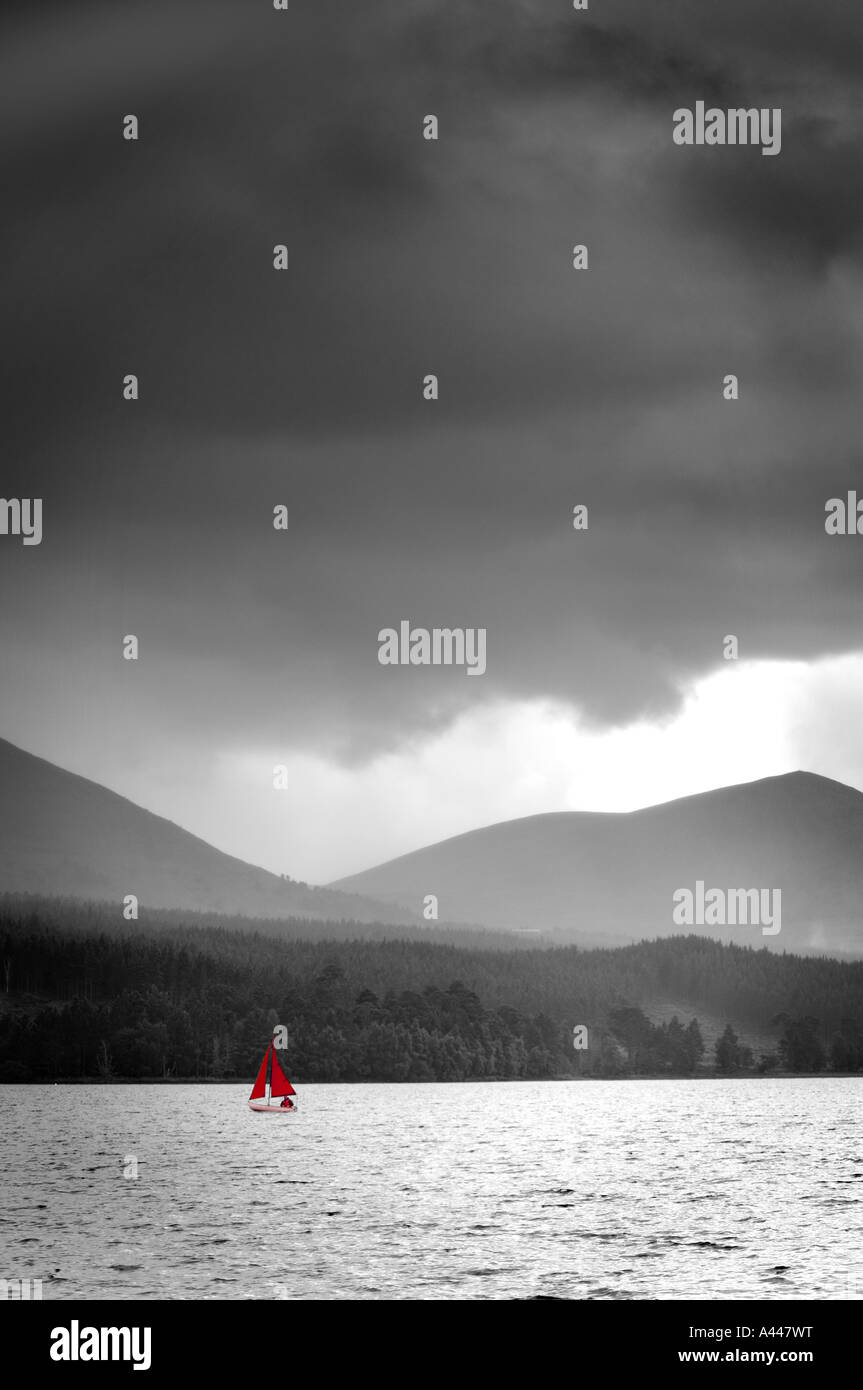 A lone boat sail upon Loch Morlich in Scotland as the weather closes in ...