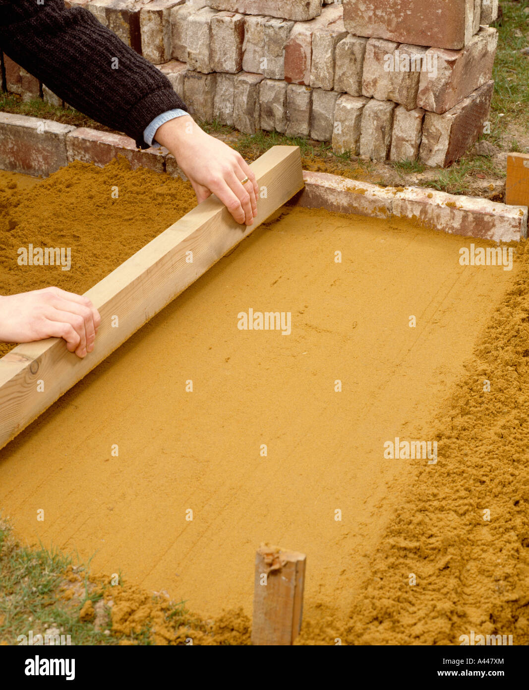 Close-up of man smoothing sand on new path before laying bricks Stock ...