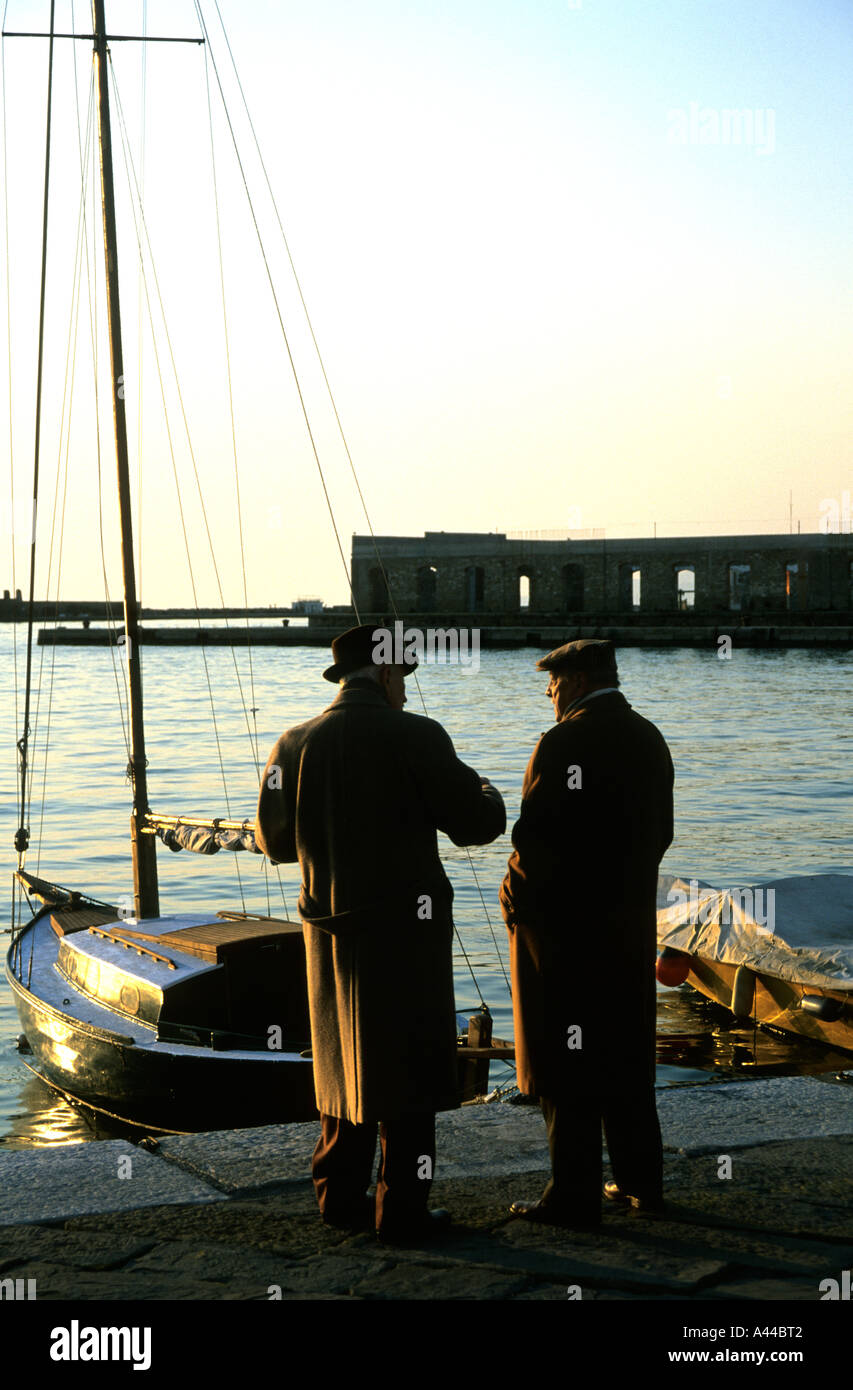 Two men in conversation by the harbour in Trieste Italy Stock Photo - Alamy