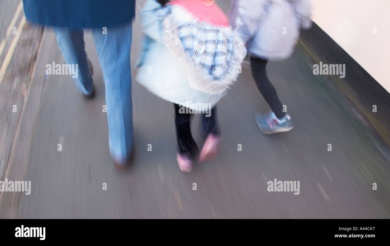 man and girls walking along pavement Stock Photo - Alamy