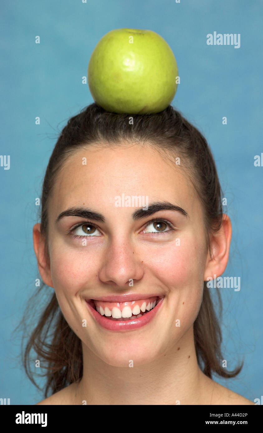 Smiling Young Woman with Apple on Head Stock Photo - Alamy