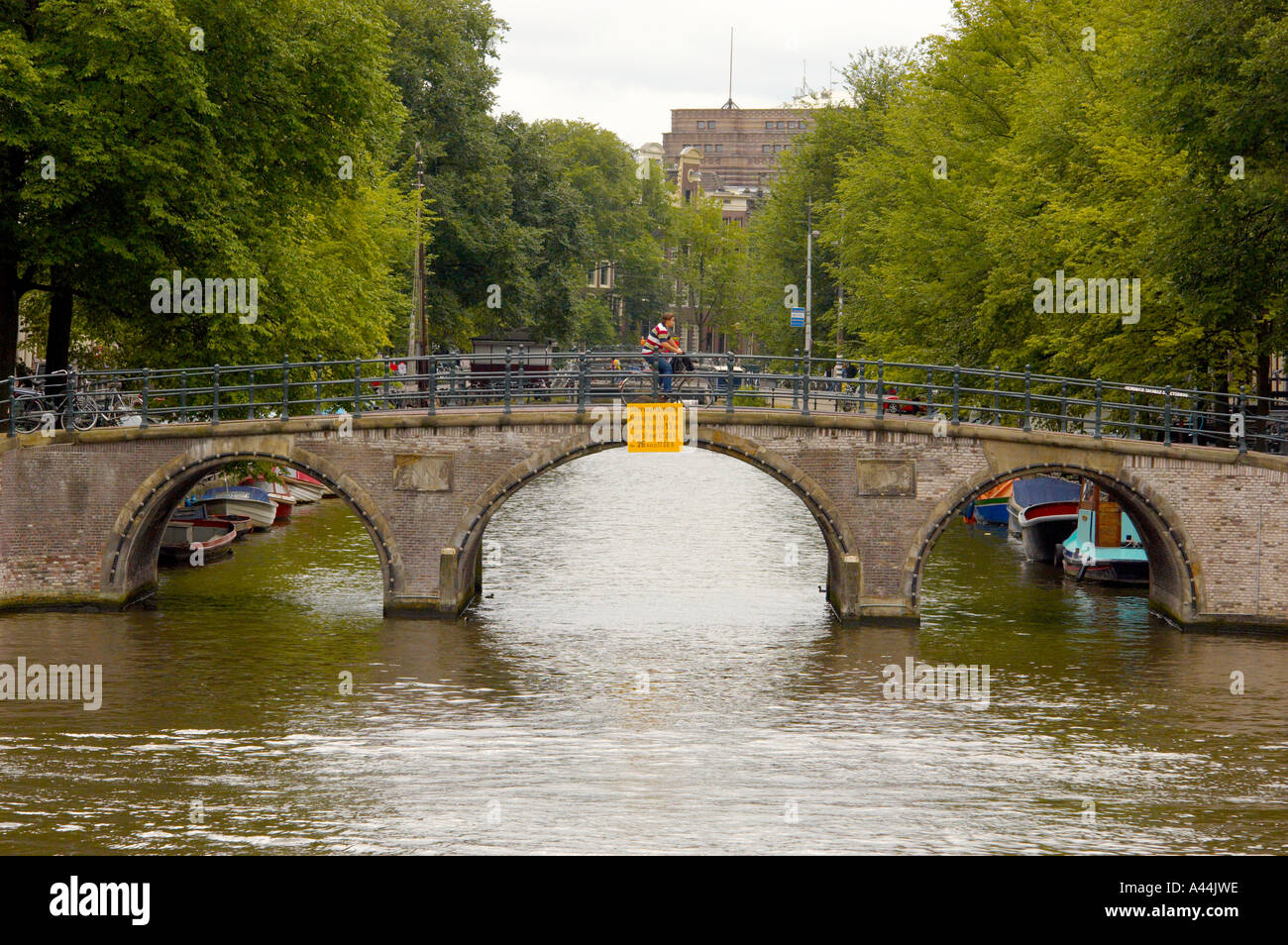 A traditional low arched bridge crossing the canal seen from the river ...