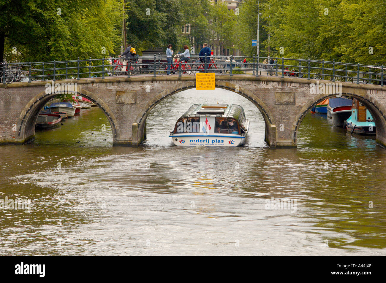 Canal boat with tourists on an excursion passing under a low bridge ...