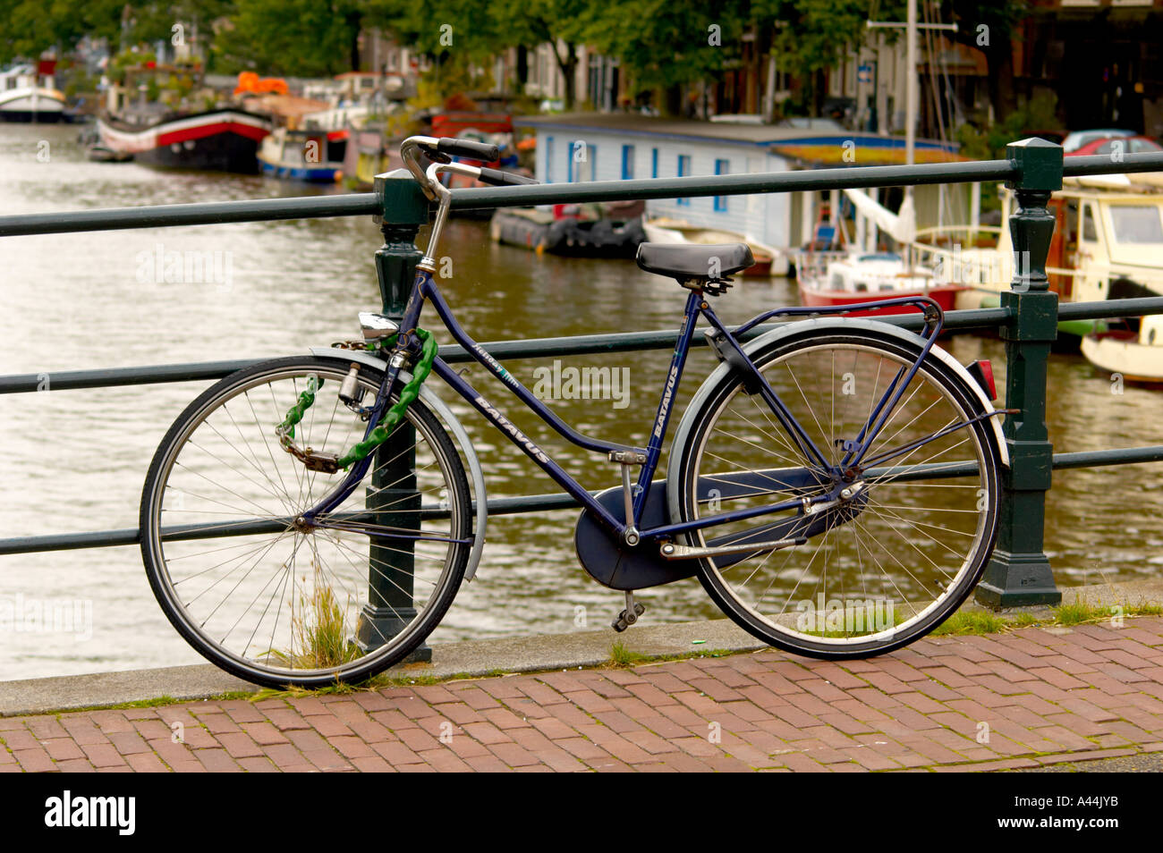 A traditional-style bicycle locked to the railing of a bridge crossing ...