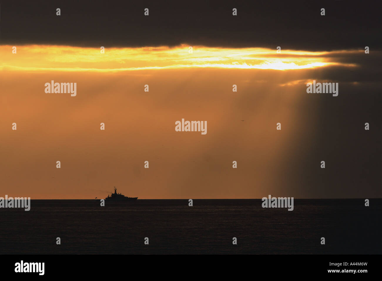 Royal Navy ship on the Horizon at sunset Stock Photo - Alamy