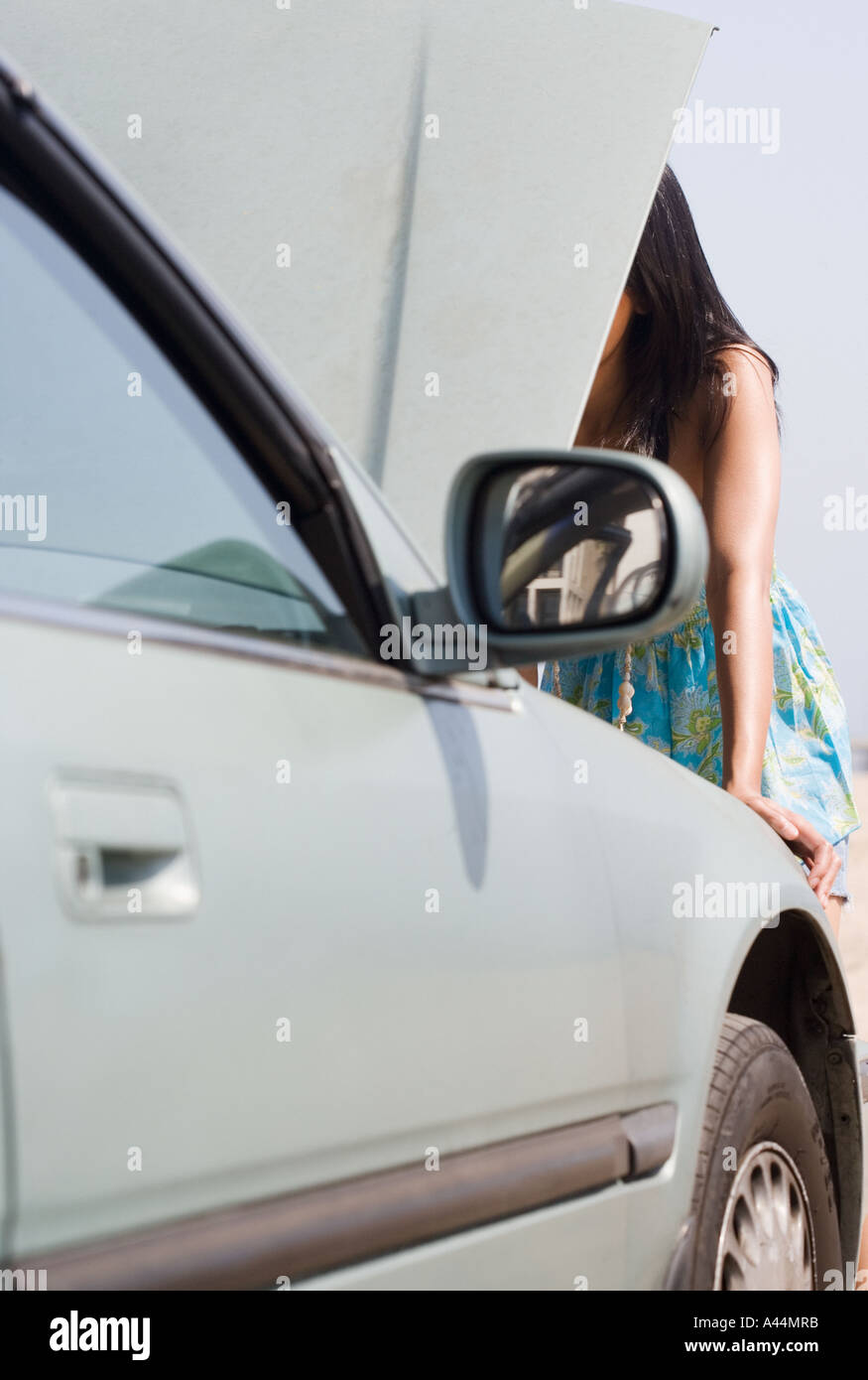 Woman looking under hood of car Stock Photo - Alamy