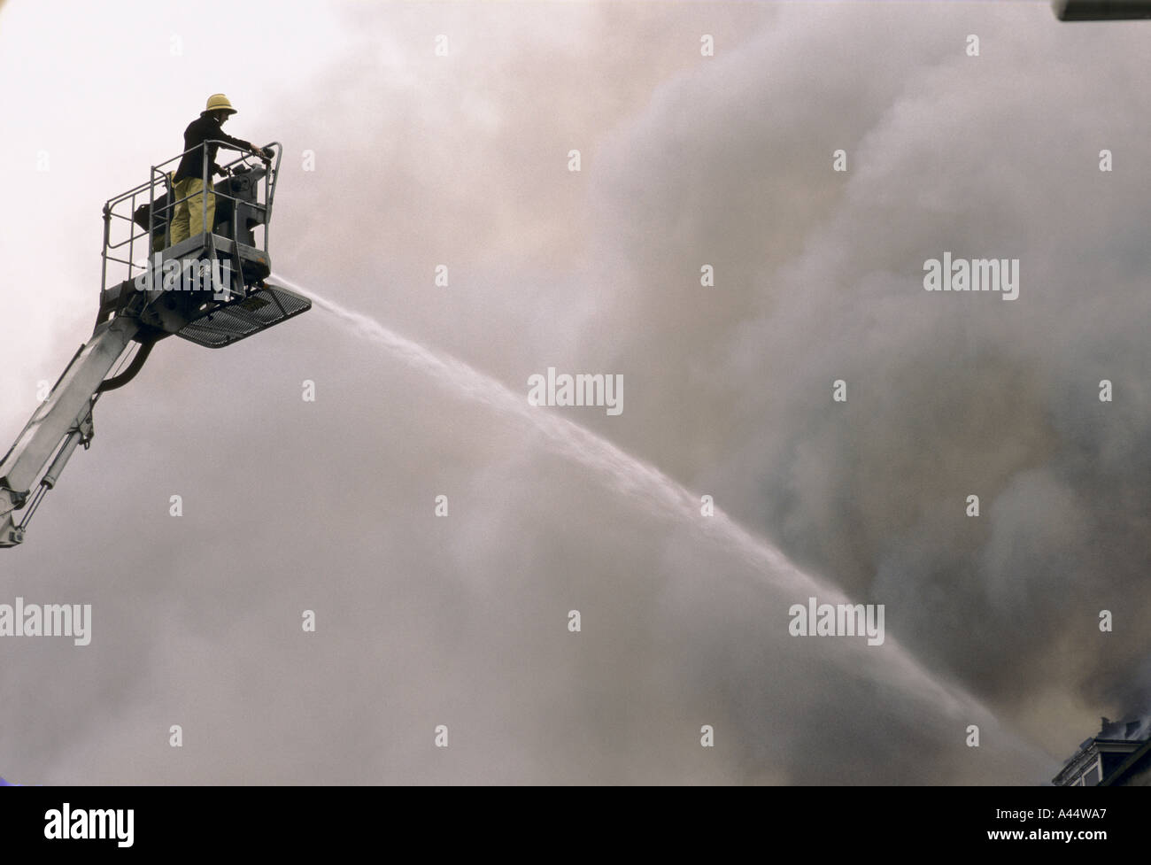 fireman in action spraying water from elevated hydraulic platform at ...