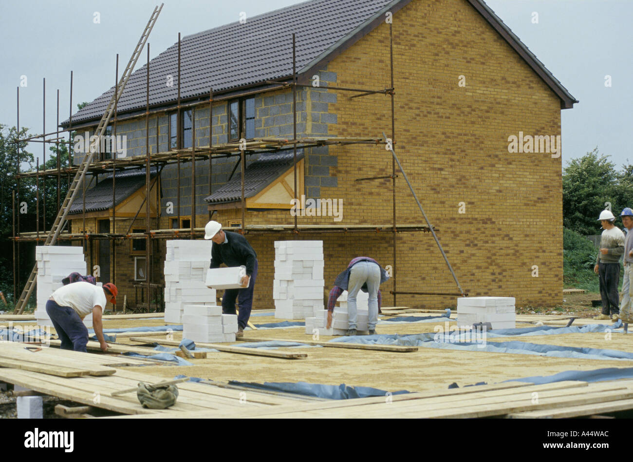 housing under construction builders carrying blocks of materials at ...
