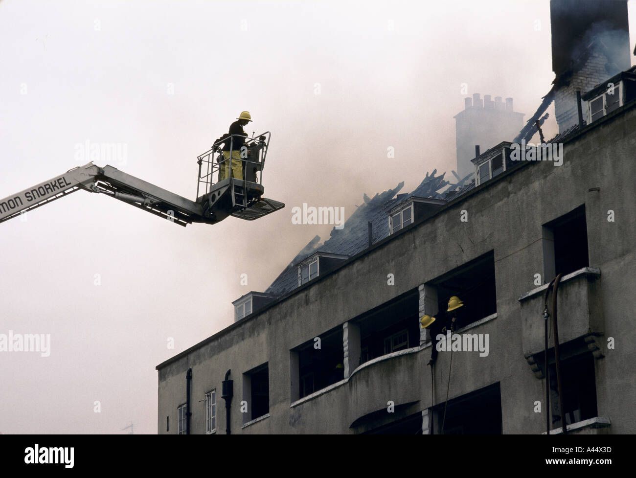 firemen in action using elevated hydraulic platform at fire in flats ...