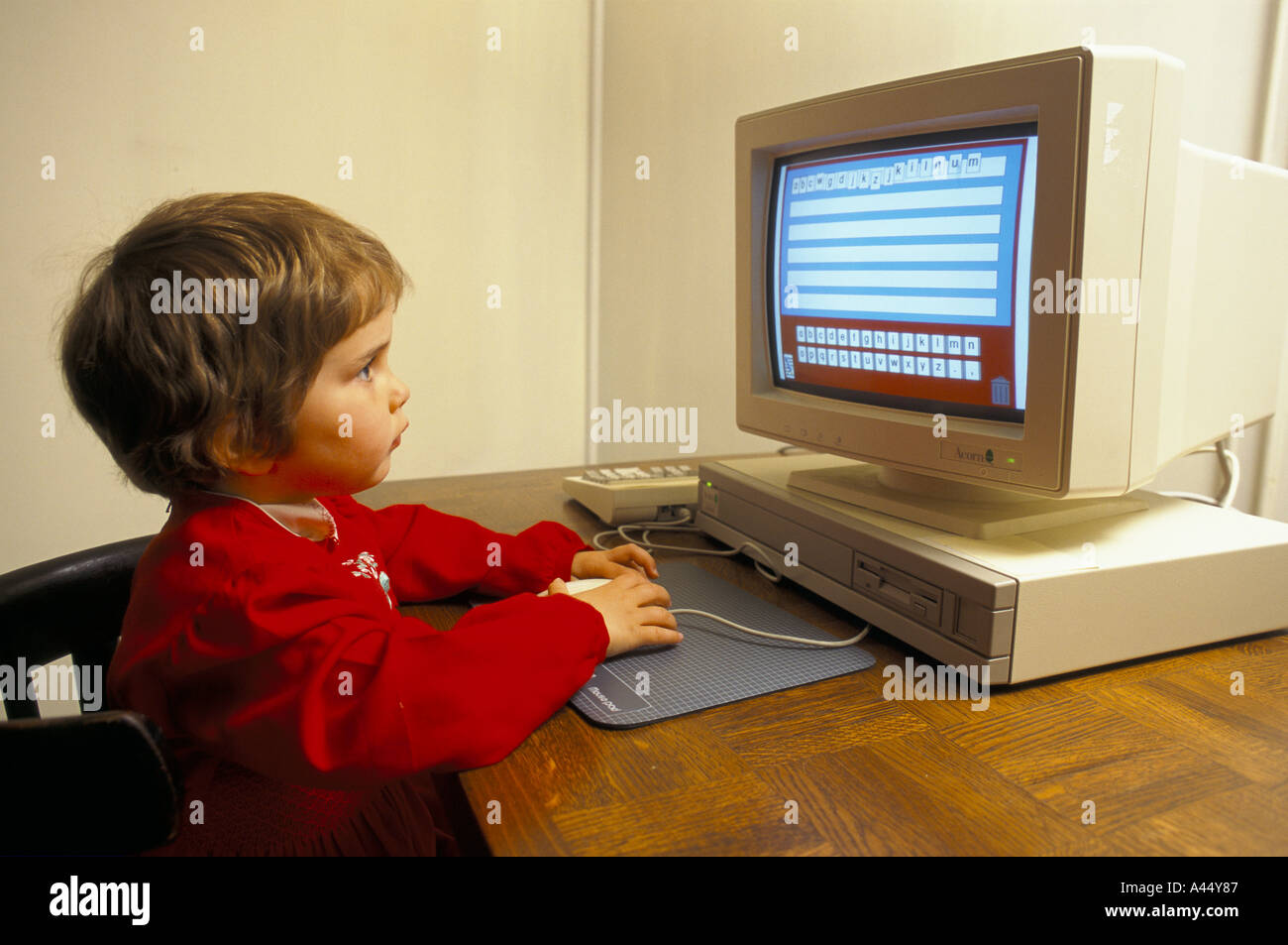 three year old child looking at computer screen learning to spell using ...