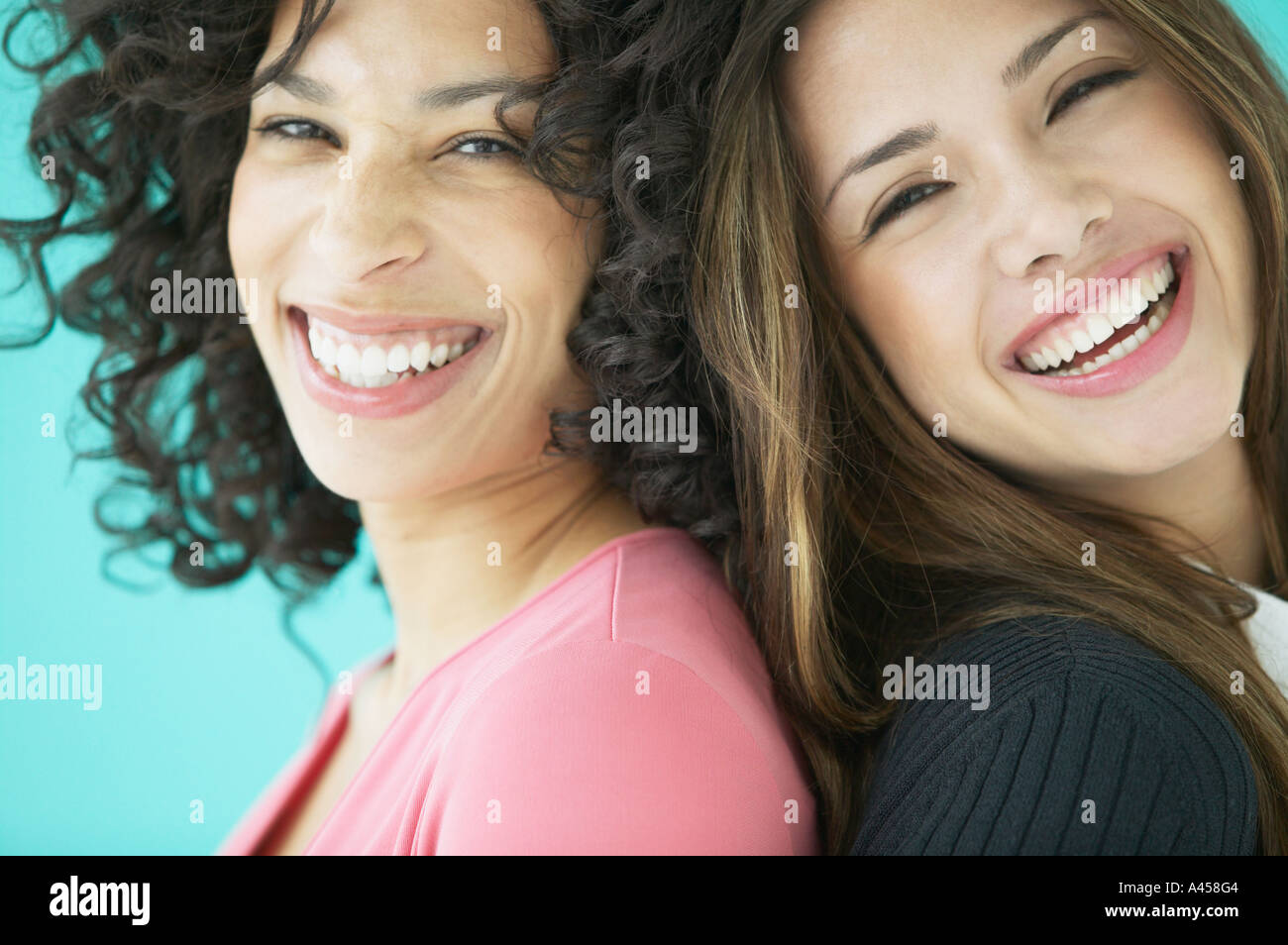 Two women smiling back to back Stock Photo - Alamy