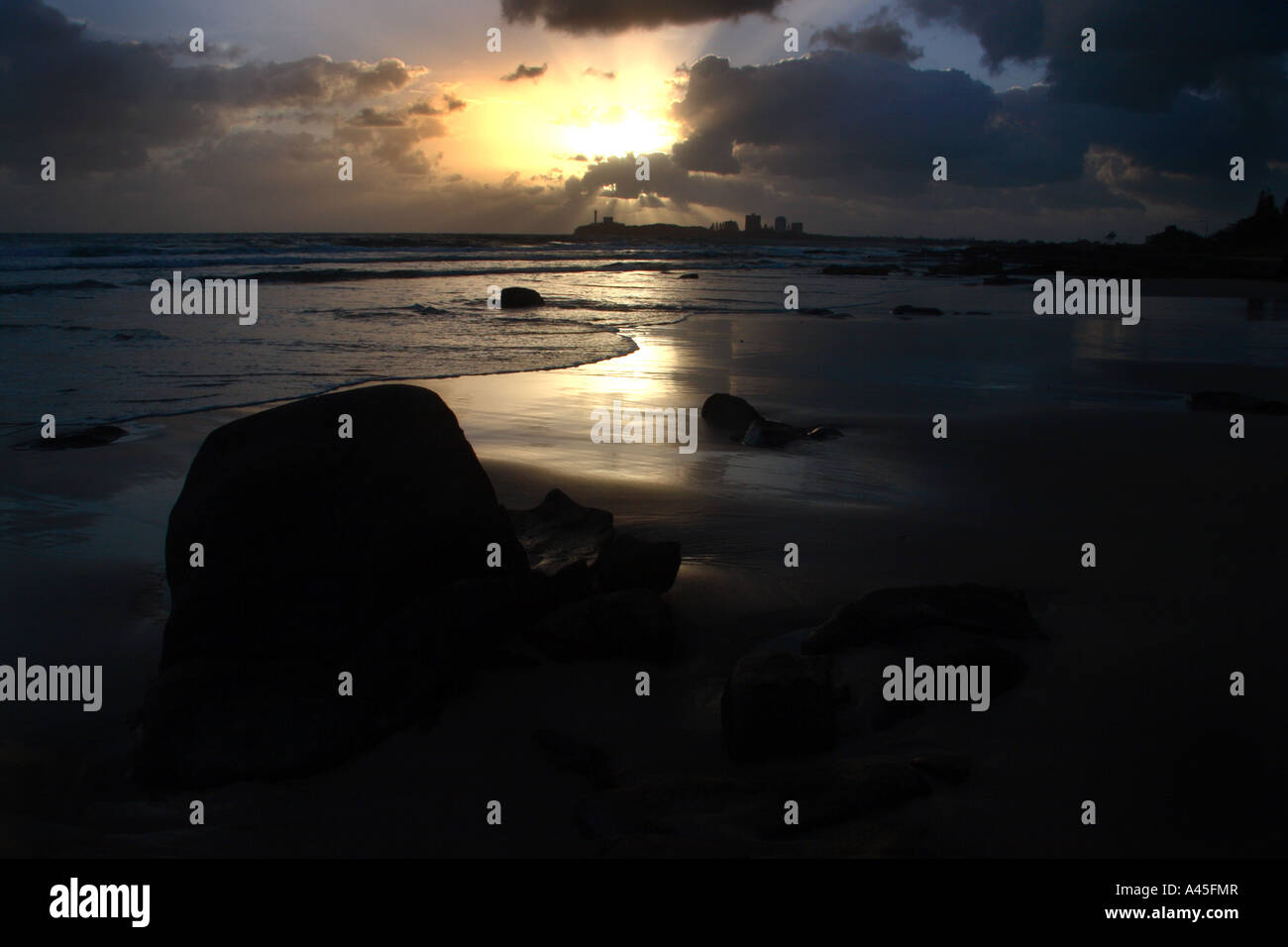 sunrise on lighthouse on beach clouds gods light rocks Stock Photo - Alamy