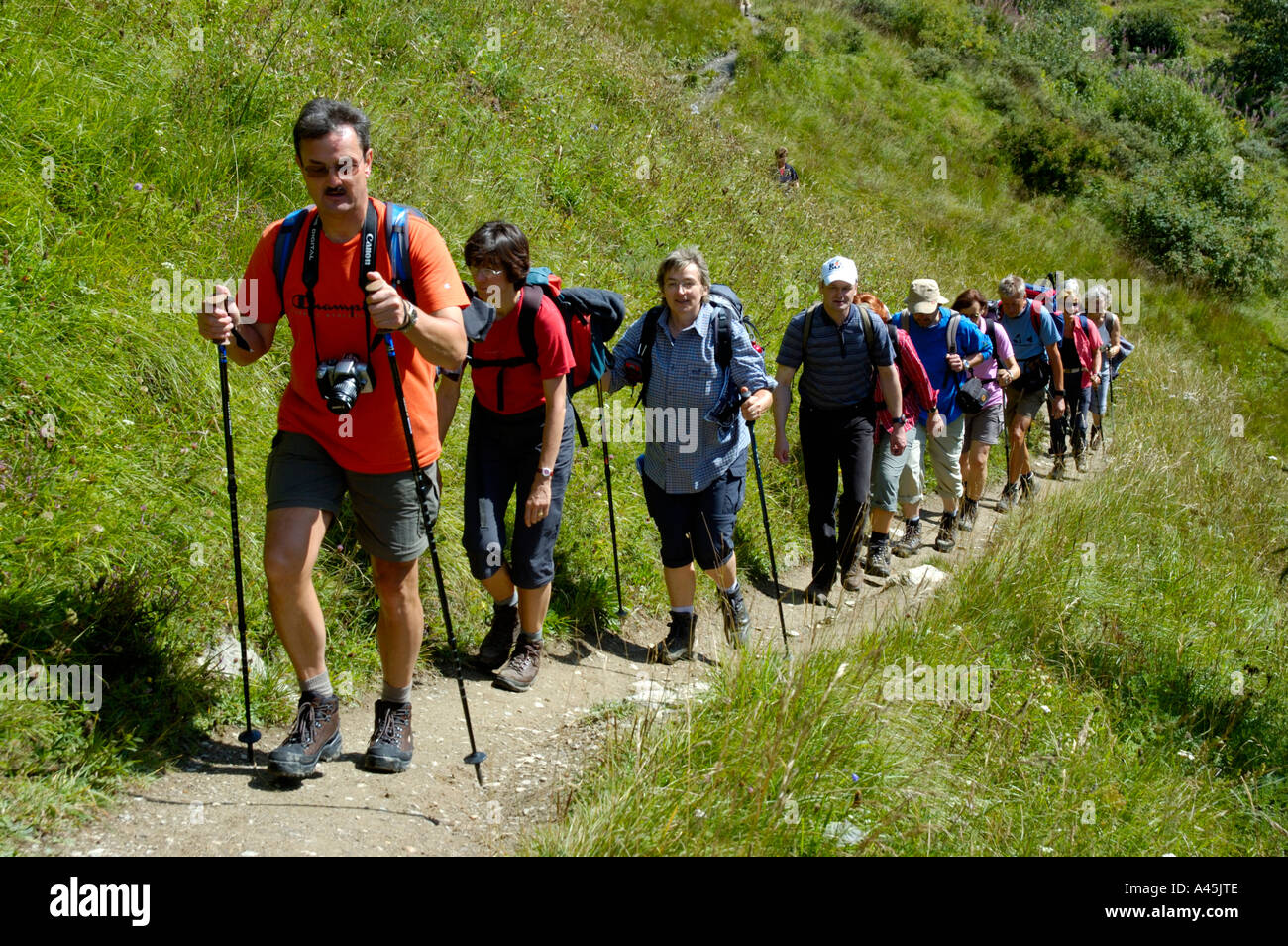 MR Hiking group one after another on a path crossing a grassy slope ...
