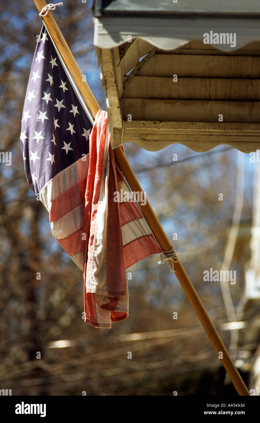 AN OLD FADED TANGLED AMERICAN FLAG HANGS FROM A POLE ON THE SIDE OF A ...