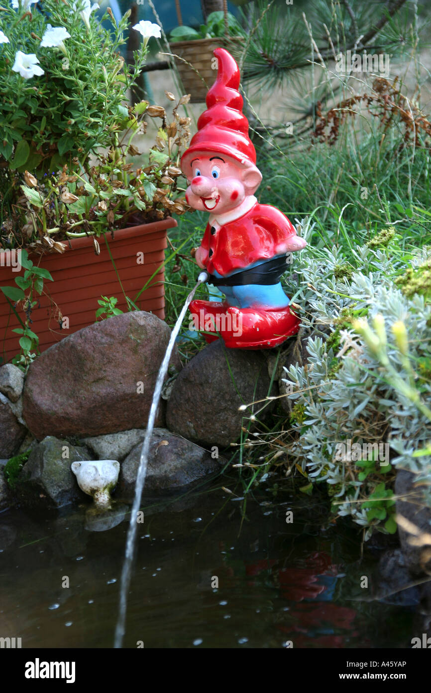 Funny dwarf pouring water into the small garden pond Stock Photo - Alamy
