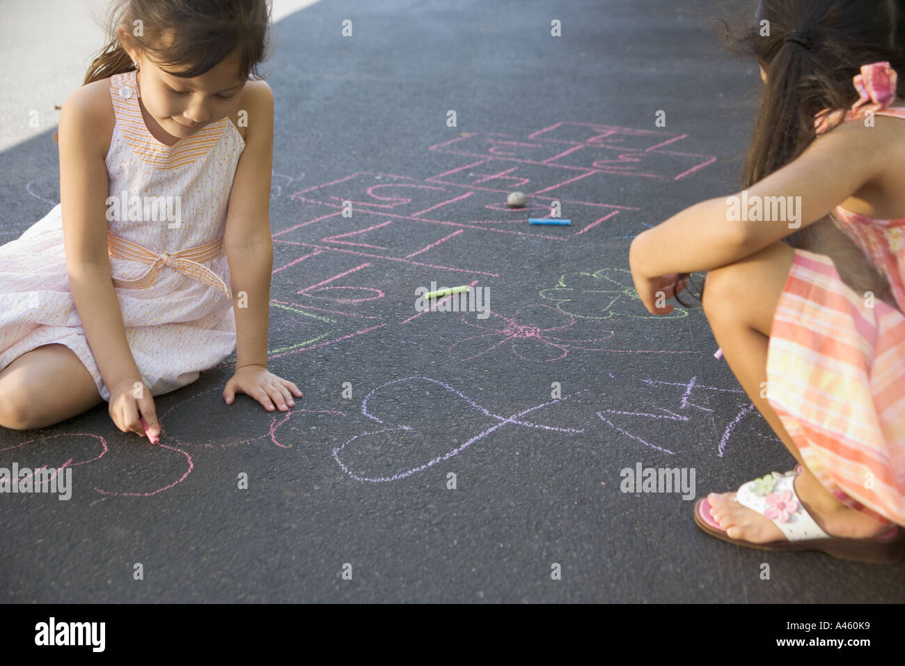 Two girls making chalk drawings Stock Photo - Alamy