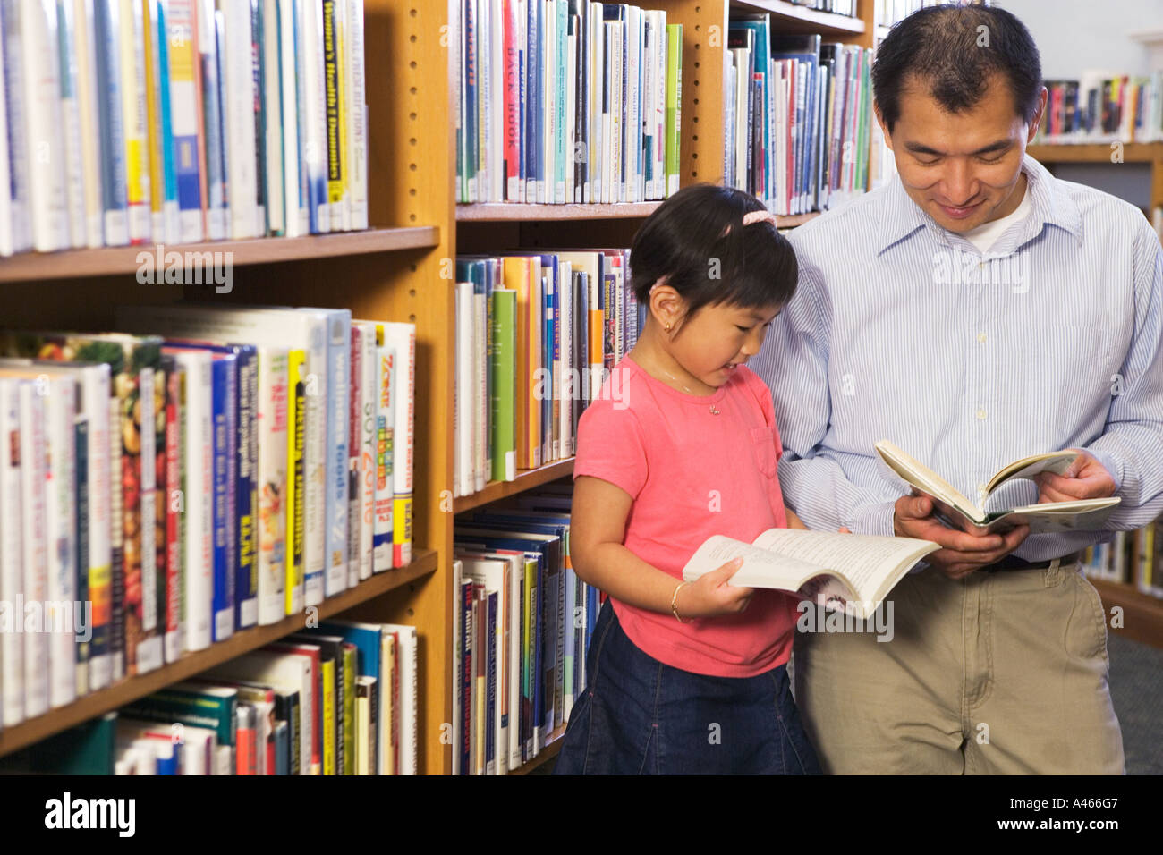 Father and daughter looking at library books Stock Photo - Alamy