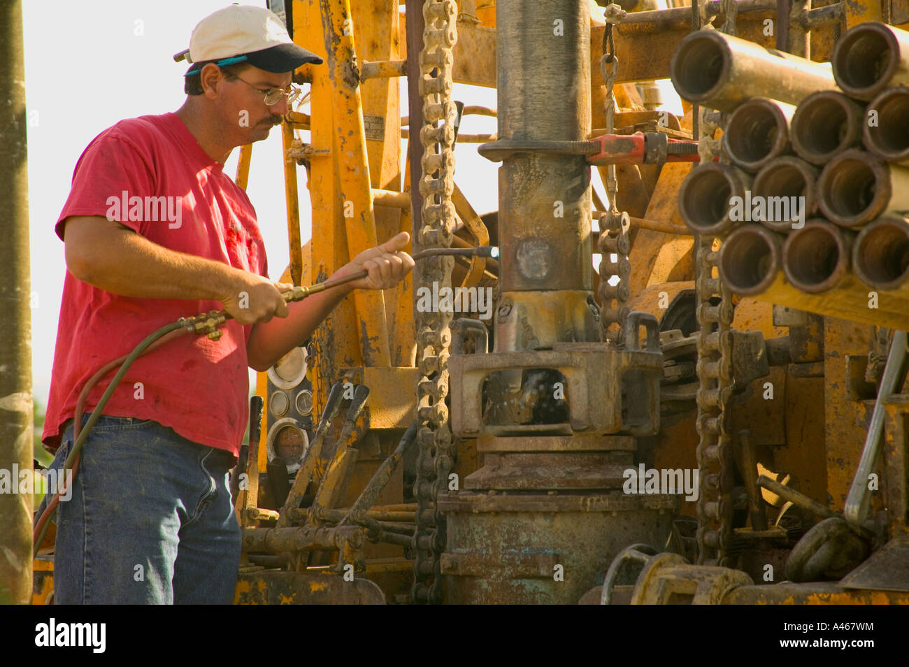 Well driller using oxyacetylene torch heating coupling on well casing ...