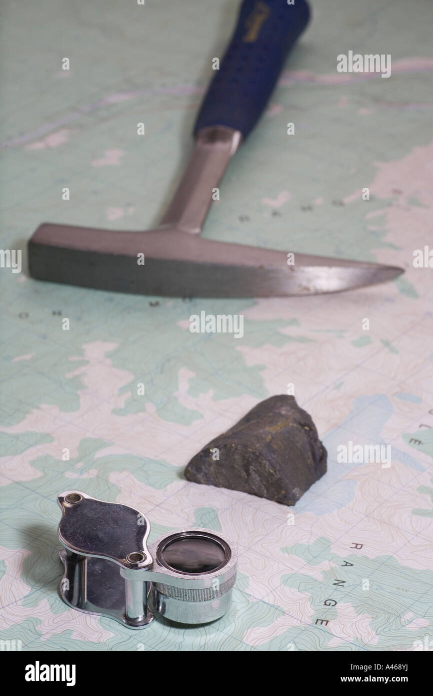 Mining concept with geologists rock hammer magnifier mineral on contour ...