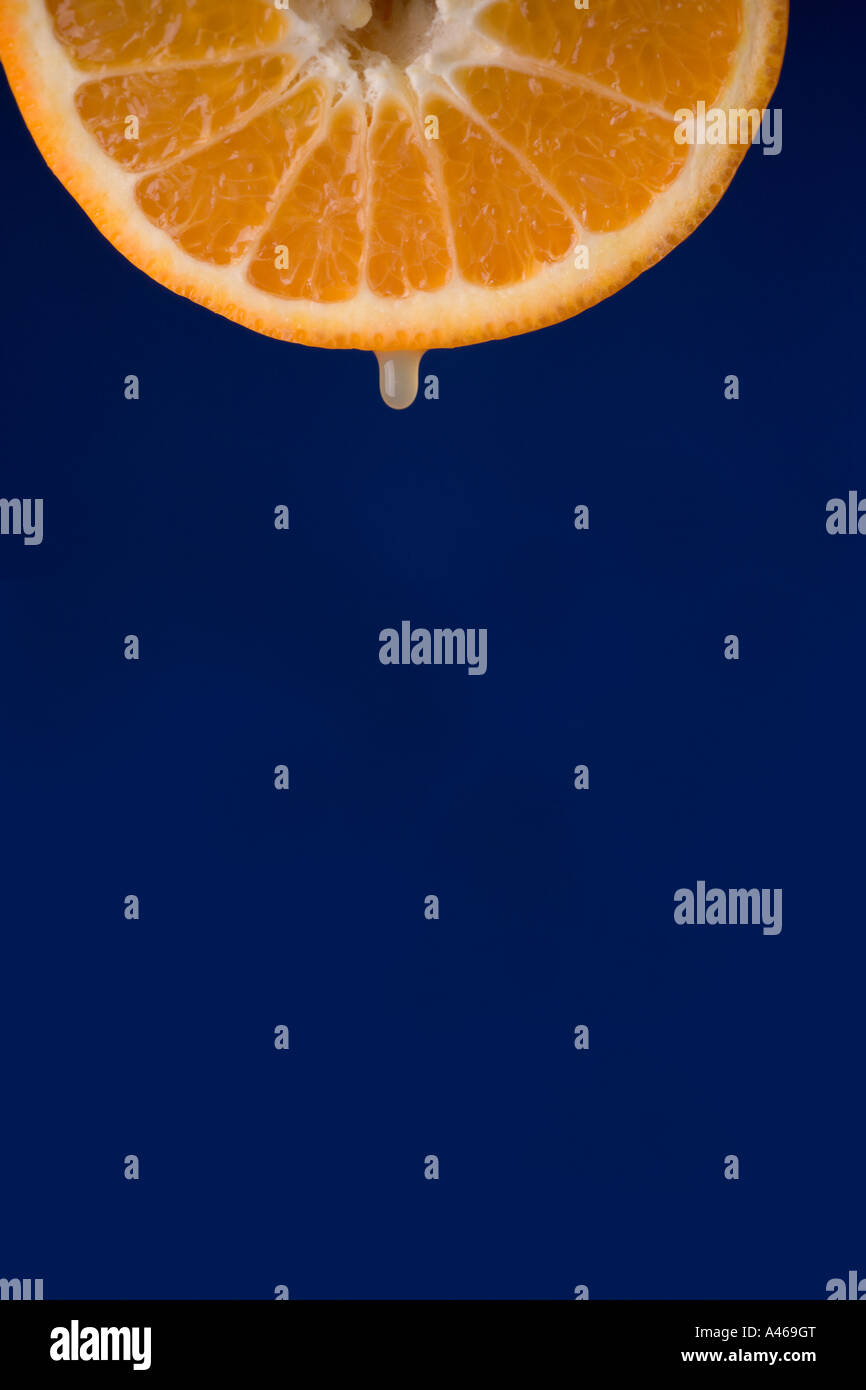 Drops of juice falling from freshly cut orange isolated on a blue ...