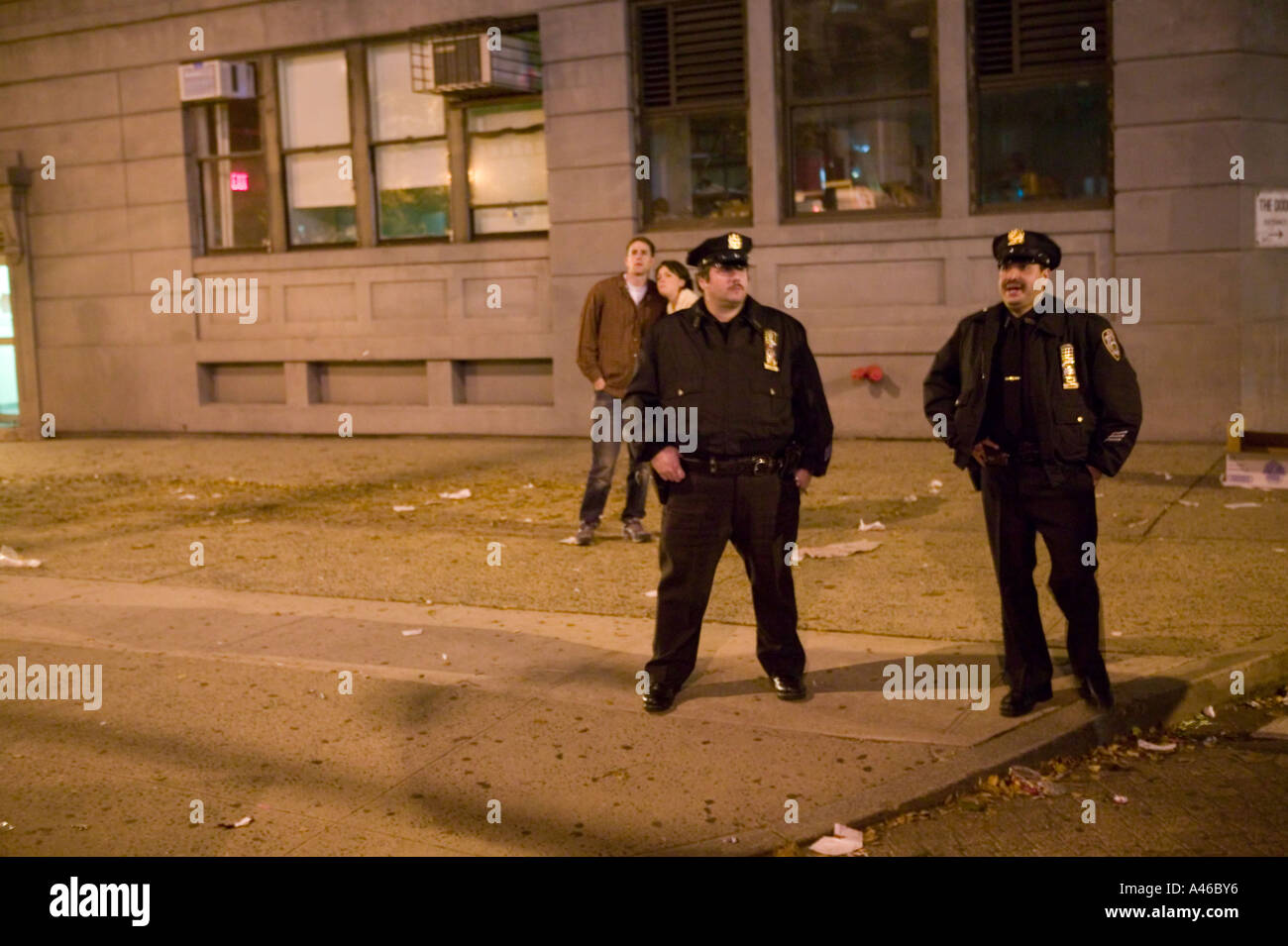 Two NYPD police officers and a couple watch street activity in New York ...