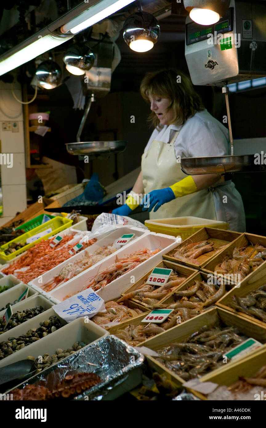 Female fishmonger selling fresh shellfish at counter in Mercado de la ...