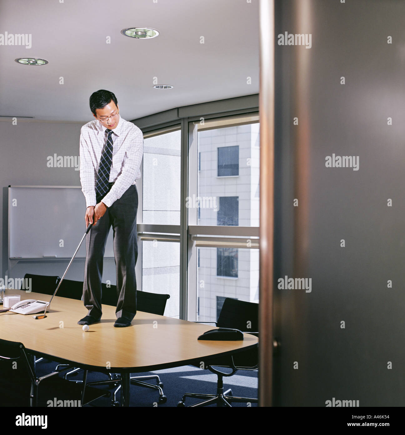 Businessman playing golf in office Stock Photo - Alamy