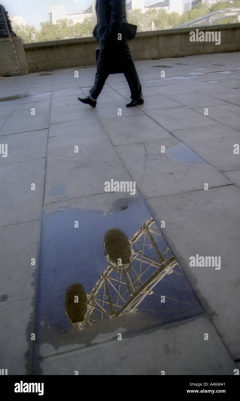 A man walks past a rain puddle reflection of the British Airways London ...