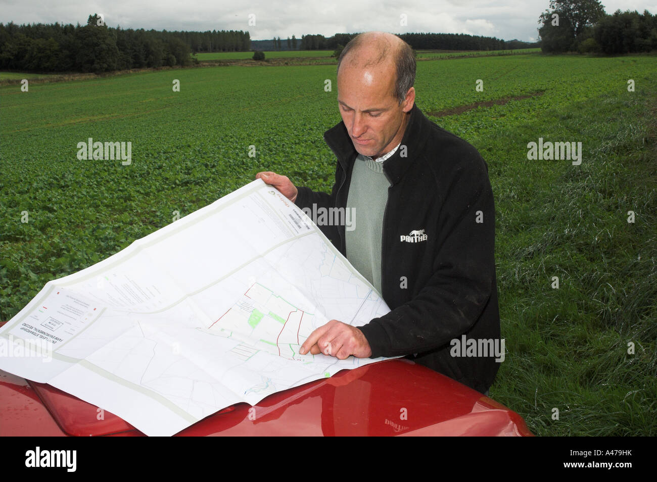 Farmer looking at maps of farm Stock Photo - Alamy