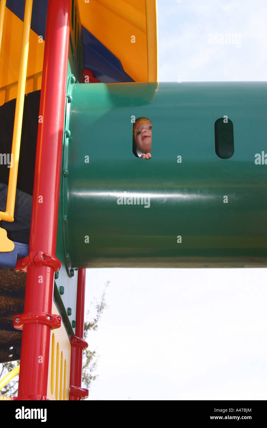 Small Child in a Green Playground Tube and Looking Through a Cut Out on ...